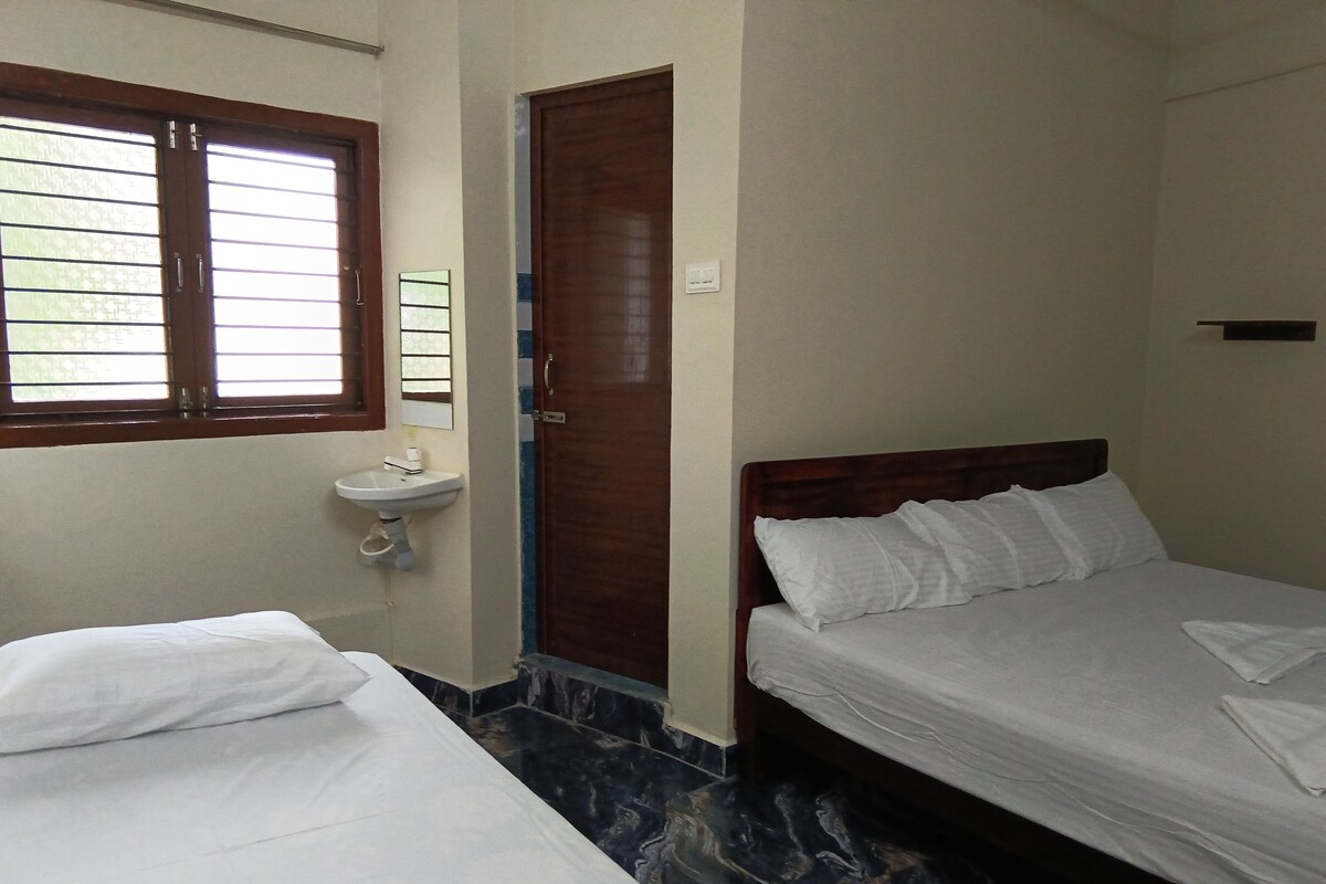 Quarto com duas camas, porta de madeira, janela com persianas e pia.