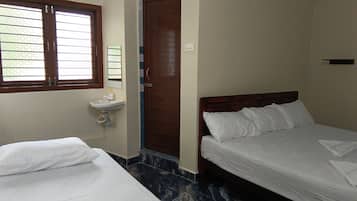 Quarto com duas camas, porta de madeira, janela com persianas e pia.