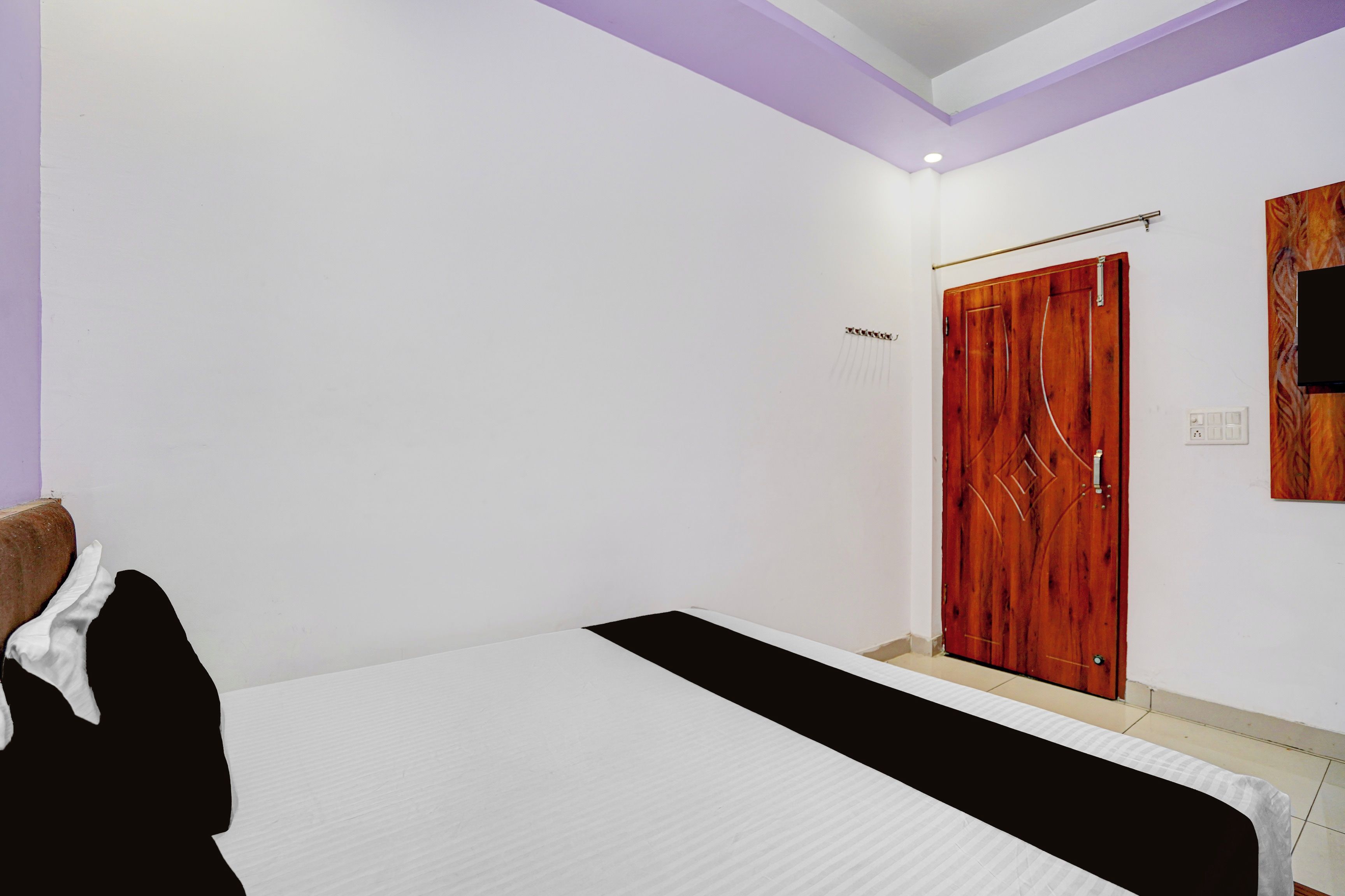 Quarto com uma cama, guarda-roupa de madeira e televisão na parede.