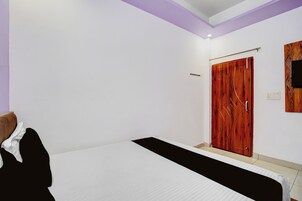 Quarto com uma cama, guarda-roupa de madeira e televisão na parede.