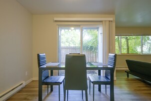 Uma área de refeições com uma mesa e quatro cadeiras, um banco e uma porta de vidro deslizante que dá para um deck.