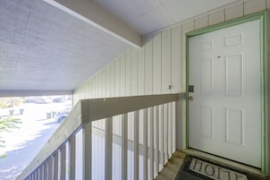Uma porta branca com moldura verde, um corrimão branco e um tapete de entrada com a palavra 'HOME'.