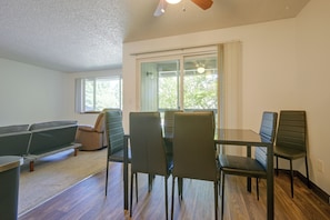 Quarto com mesa de jantar, cadeiras, sofá e janela com persianas.