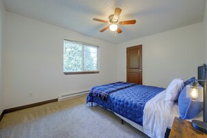 Quarto com cama, ventoinha no teto, janela e porta.