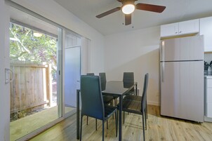Uma cozinha com geladeira, mesa de jantar com cadeiras e ventilador de teto.