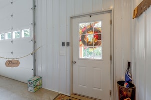Uma porta de garagem com uma placa escrita 'Propriedade Privada, Não Entre', uma janela com um arranjo decorativo e um balde com uma lona azul.