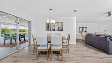 Um espaço de estar moderno com área de jantar, sofá e vista para o exterior.