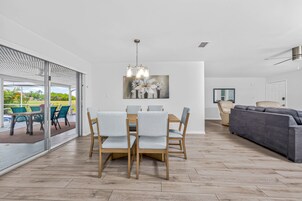 Um espaço de estar moderno com área de jantar, sofá e vista para o exterior.