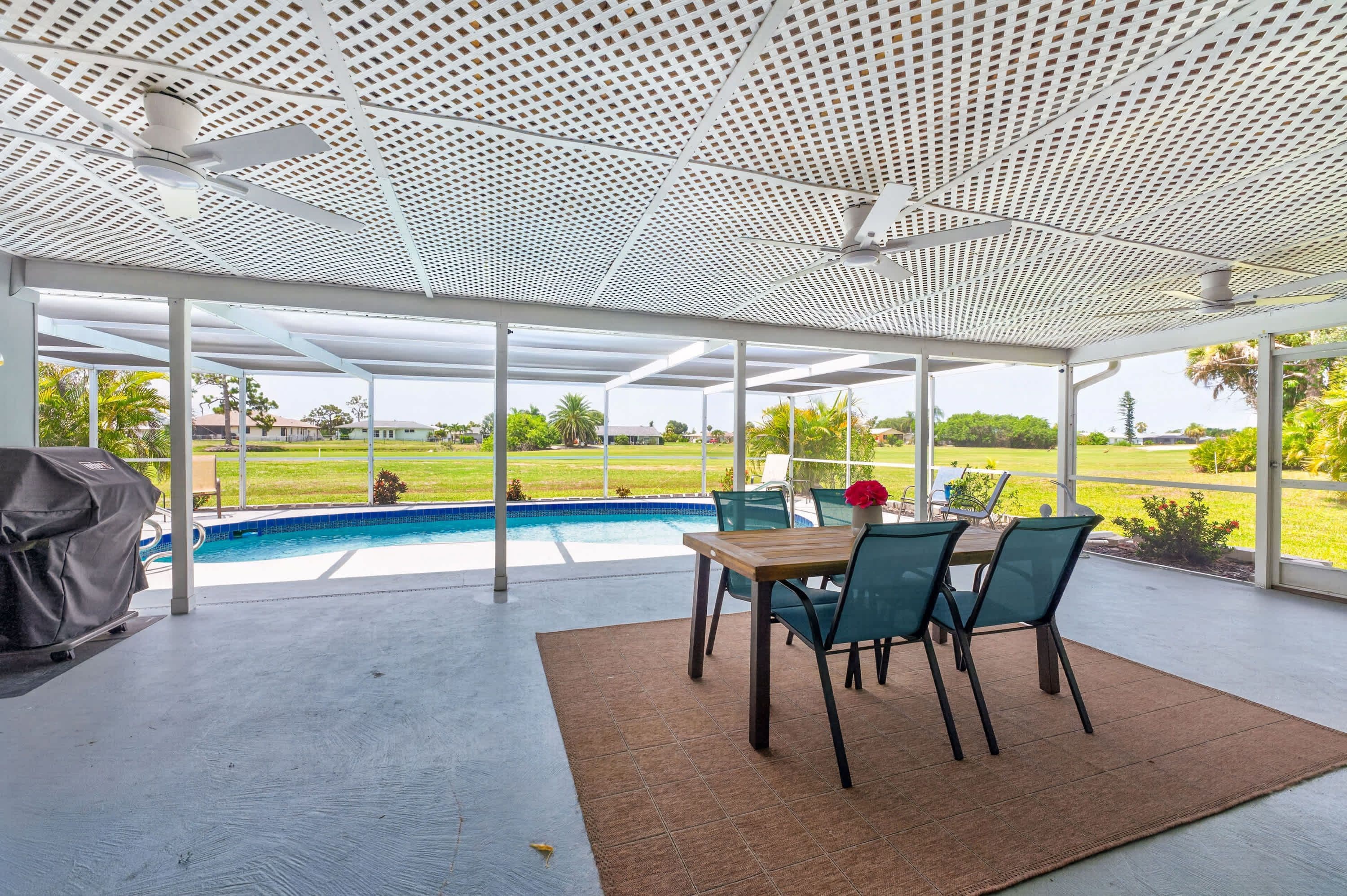 Um terraço coberto ao ar livre com piscina, cadeiras e churrasqueira.