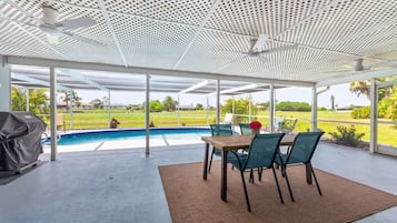 Um terraço coberto ao ar livre com piscina, cadeiras e churrasqueira.