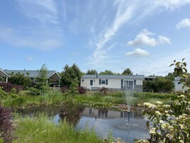 Área residencial com casas, um lago com nenúfares e céu claro.