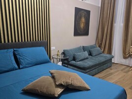 Quarto com cama, sofá, uma mesinha e uma obra de arte na parede.