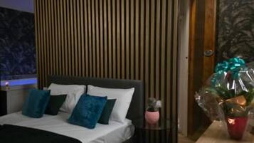 Quarto com cama, mesa de cabeceira e luminária na parede.