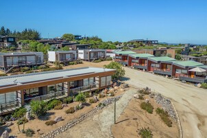 Zona residencial com casas modernas, estrada de terra e céu claro.