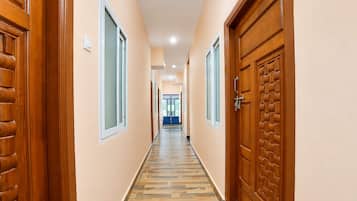 Um corredor com portas e janelas de madeira, que leva a uma porta azul no final.