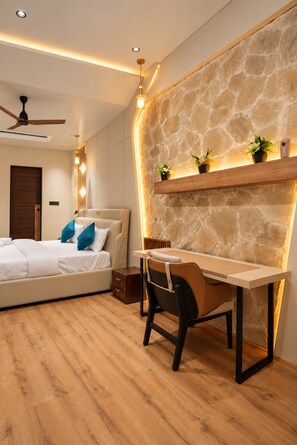 Quarto moderno com cama, escrivaninha, cadeira e parede de destaque em pedra.