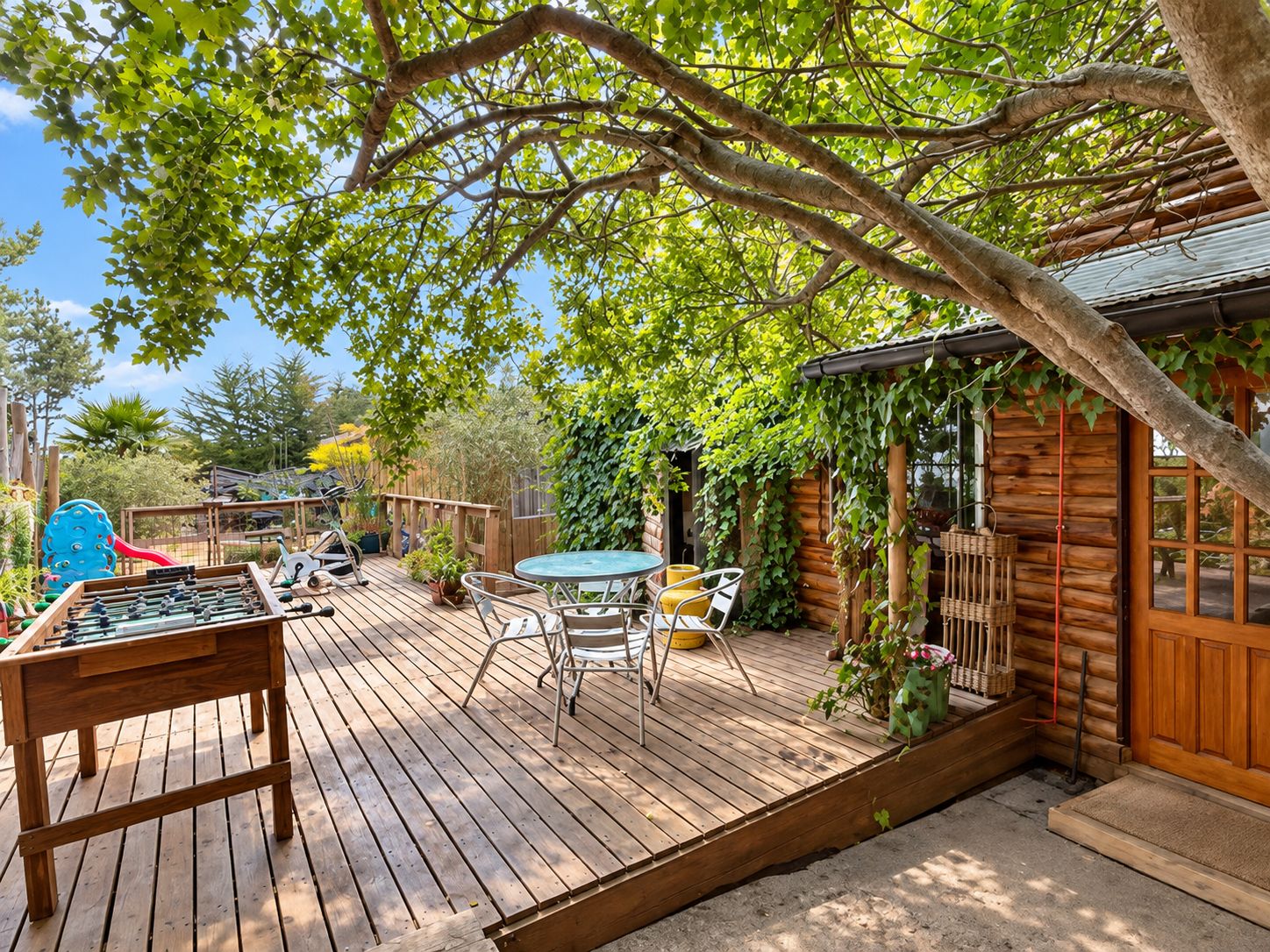 Um deck de madeira com móveis de exterior, mesa e cadeiras.