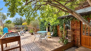 Um deck de madeira com móveis de exterior, mesa e cadeiras.