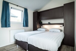 Quarto com cama, cortinas, radiador e janela.