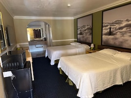Quarto de hotel com duas camas, televisão e obras de arte nas paredes.