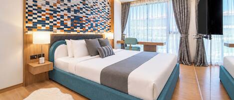 Quarto de hotel moderno com uma cama grande, uma escrivaninha, uma cadeira, uma televisão e uma parede com padrão.