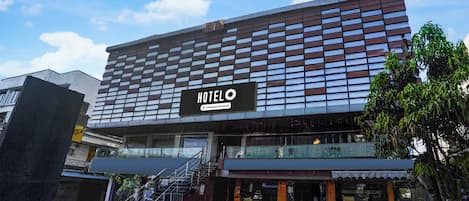 Hotel com fachada moderna, placa indicando serviço corporativo e escadaria que leva à entrada.