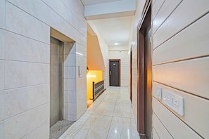 Corredor com paredes revestidas de azulejos, chão de mármore e porta com placa de identificação.