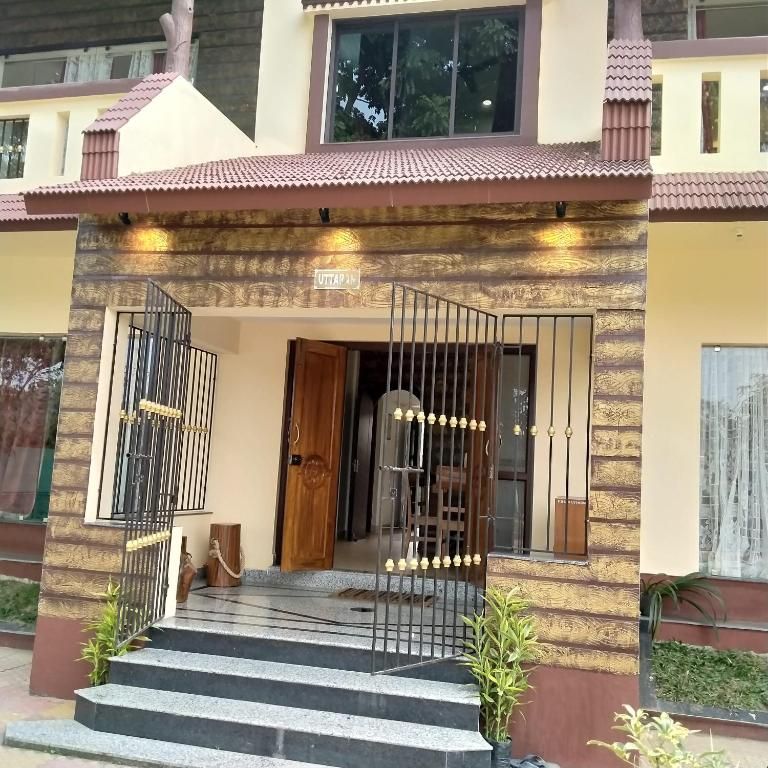 Um edifício de dois andares com escadaria que leva à entrada, porta frontal com grade e pequena varanda.