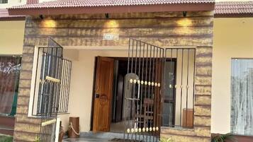 Um edifício de dois andares com escadaria que leva à entrada, porta frontal com grade e pequena varanda.