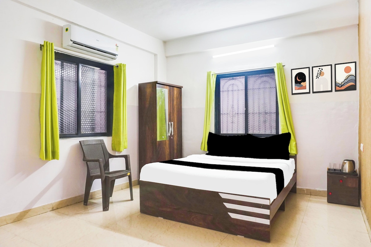 Quarto com cama, cadeira, ar condicionado, guarda-roupa e janela com cortinas.