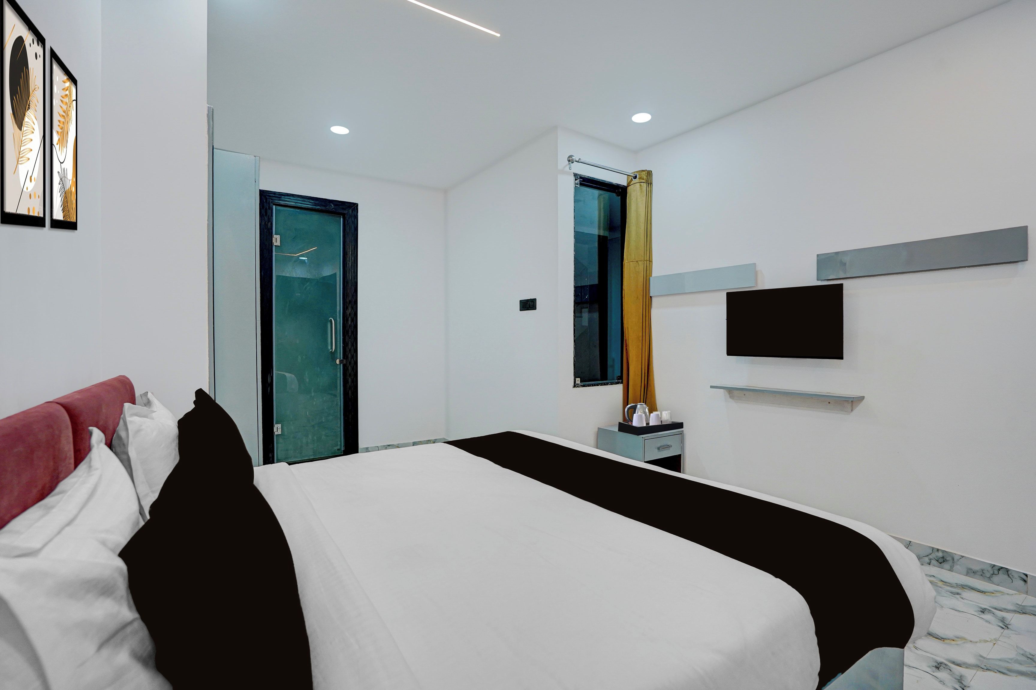 Quarto de hotel moderno com cama, mesa de cabeceira, televisão e área de chuveiro.