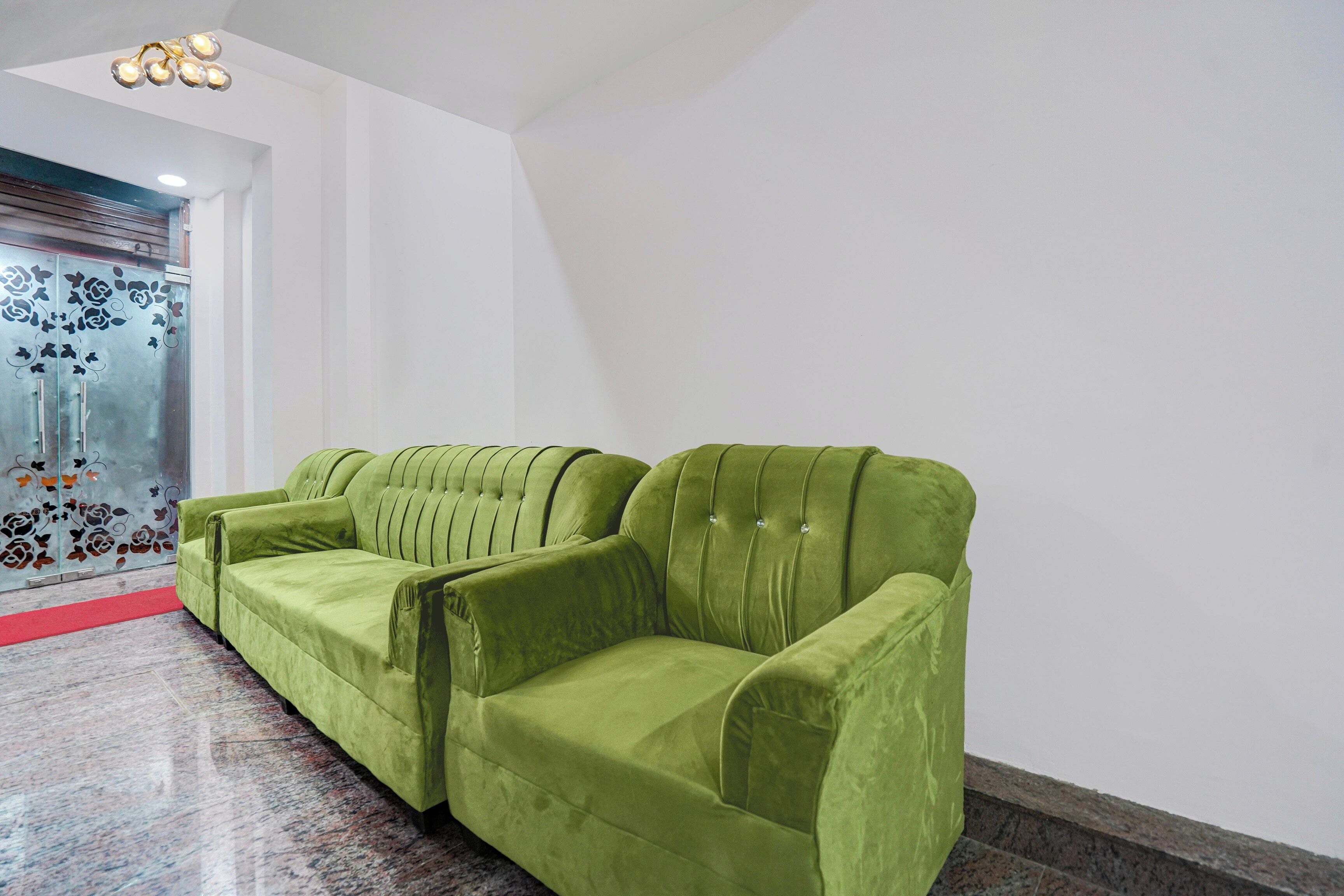 Um sofá verde num quarto com carpete vermelho e porta de vidro com desenhos florais.