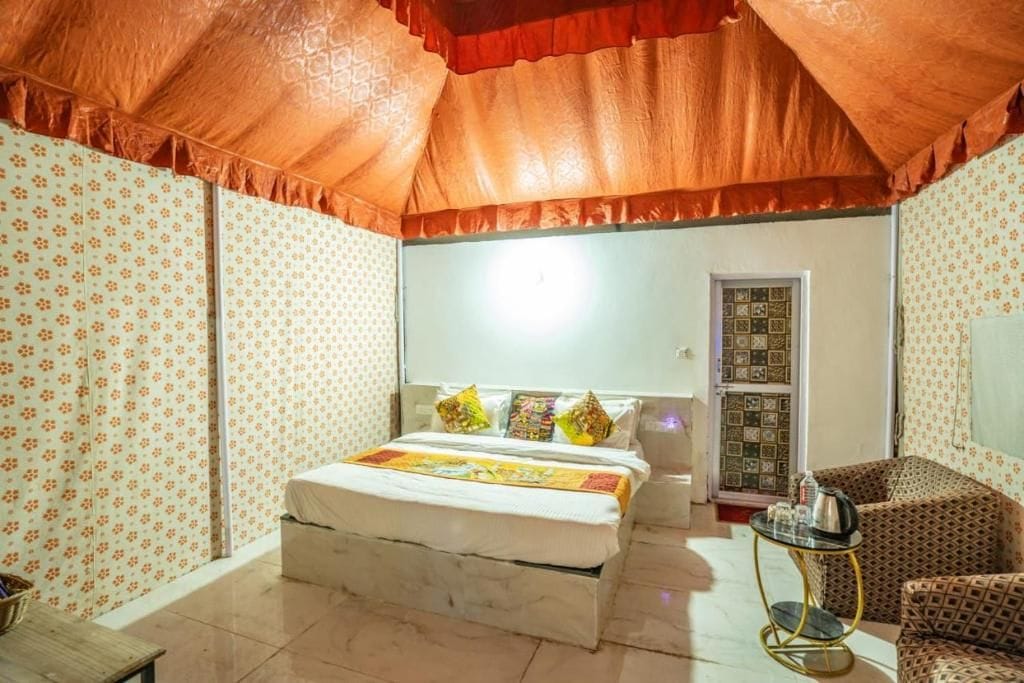 Quarto com cama, uma mesinha, uma cadeira e um papel de parede estampado.