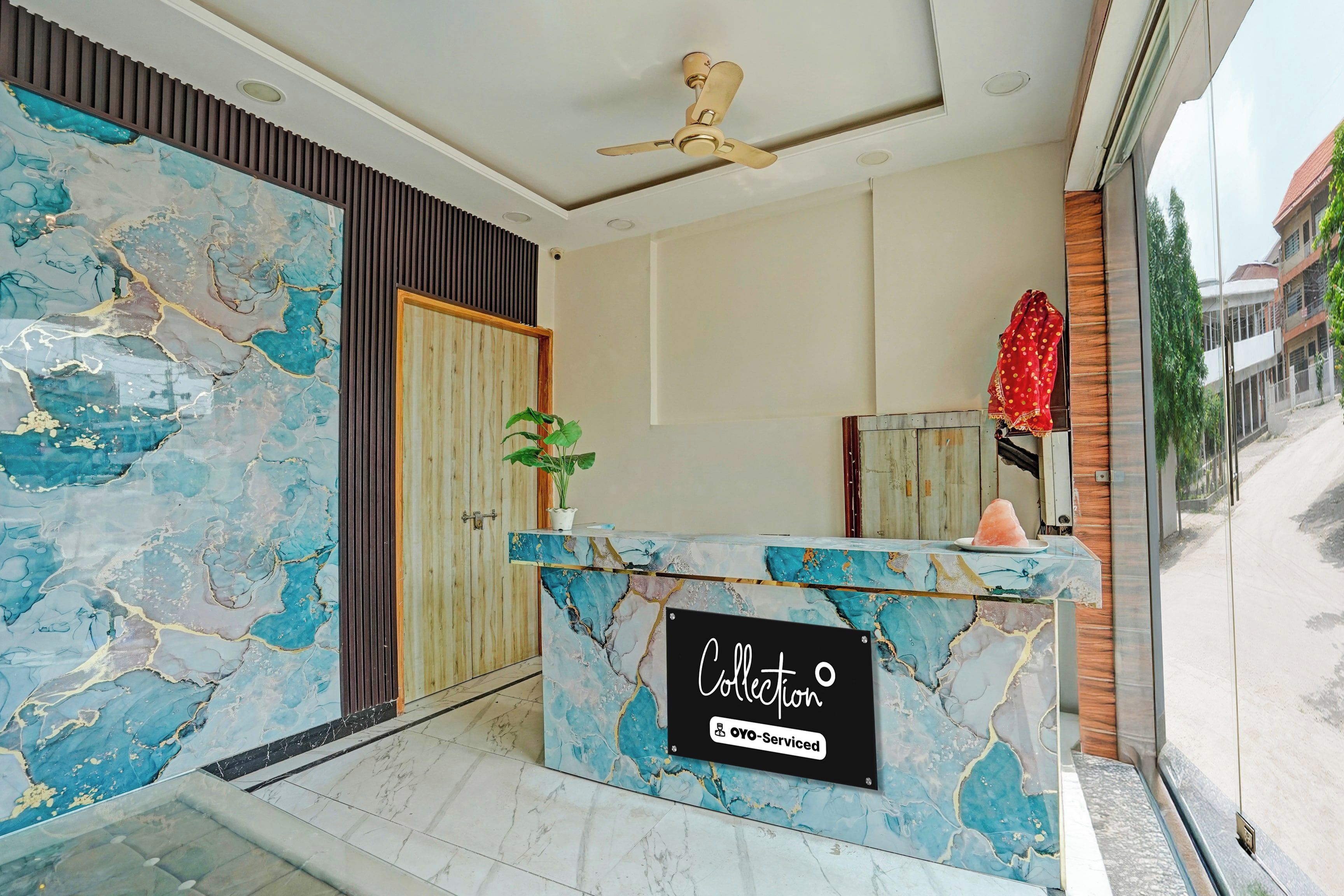 Um balcão de recepção com design em mármore, um ventilador de teto e uma porta com painel de madeira.