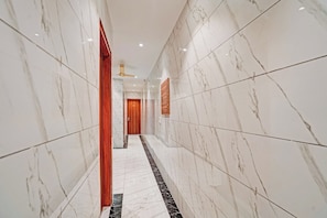 Corredor com paredes de mármore e porta de madeira no final.