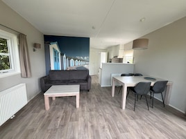 Uma sala de estar moderna com sofá, mesa de centro e um espaço de jantar com cadeiras e mesa.