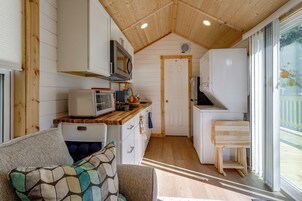 Cozinha compacta com armários de madeira, micro-ondas, torradeira e geladeira.
