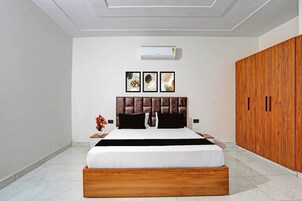 Quarto com uma cama, um guarda-roupa de madeira e três quadros na parede.