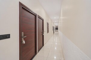Um corredor com duas portas de madeira, um interruptor de luz e um leitor de cartão-chave.