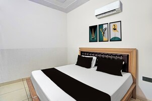 Quarto com cama, cabeceira e obras de arte na parede.