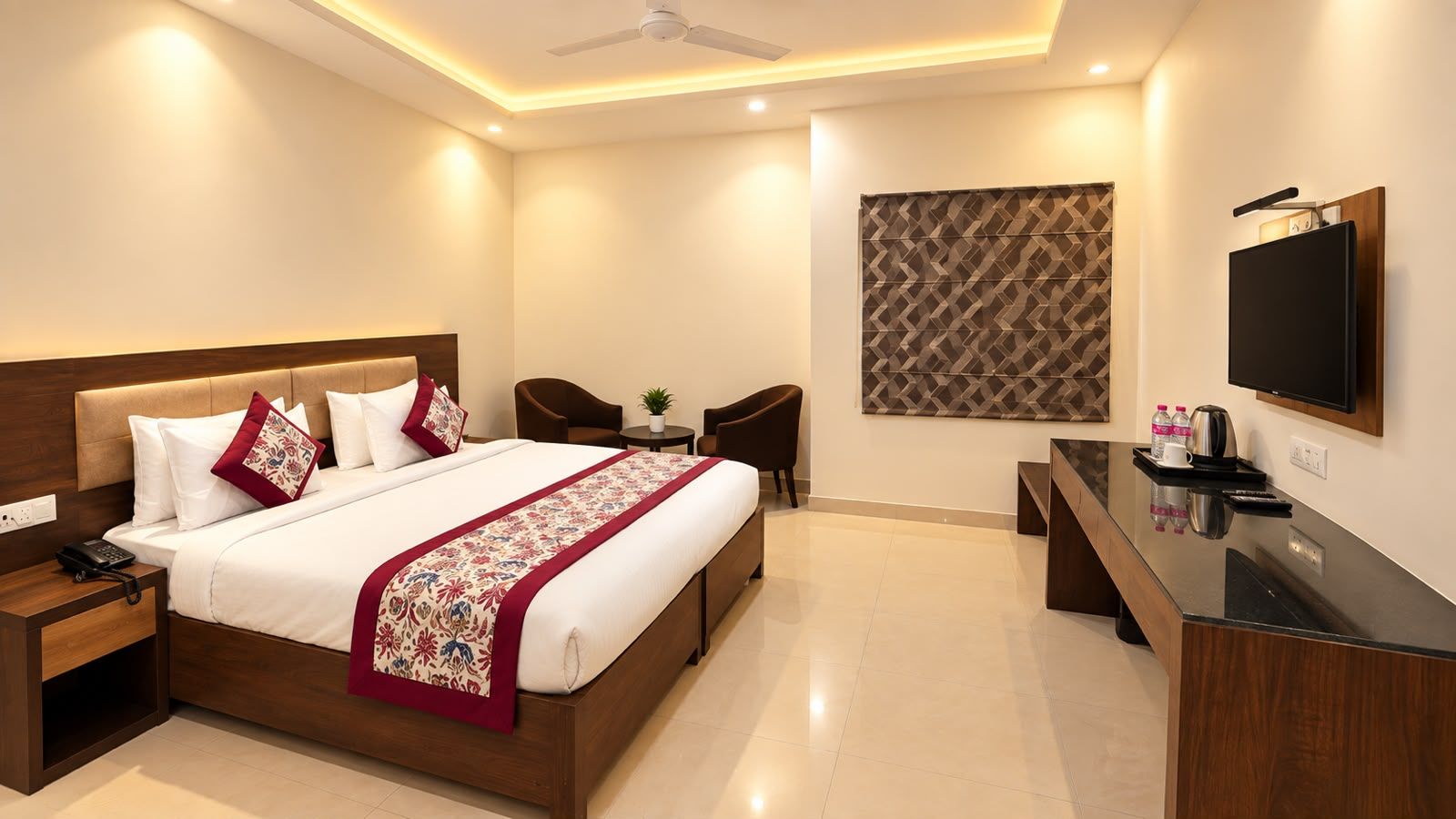Quarto de hotel moderno com uma cama grande, escrivaninha, cadeira, televisão e banheiro.