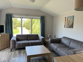 Sala de estar moderna com um sofá, uma mesa de centro e uma TV sobre um armário de madeira.
