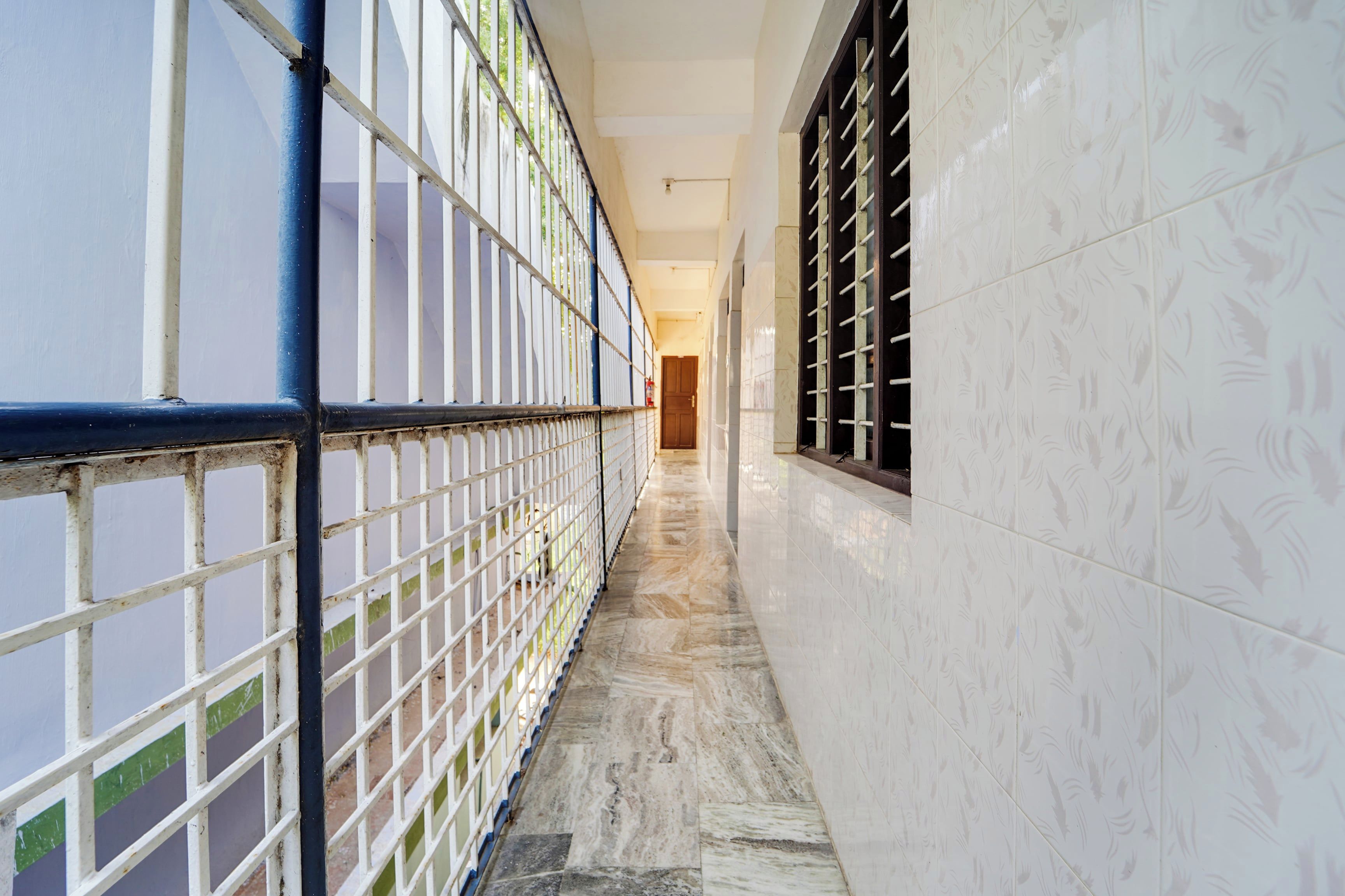 Corredor com paredes revestidas de azulejos e um corrimão de metal.