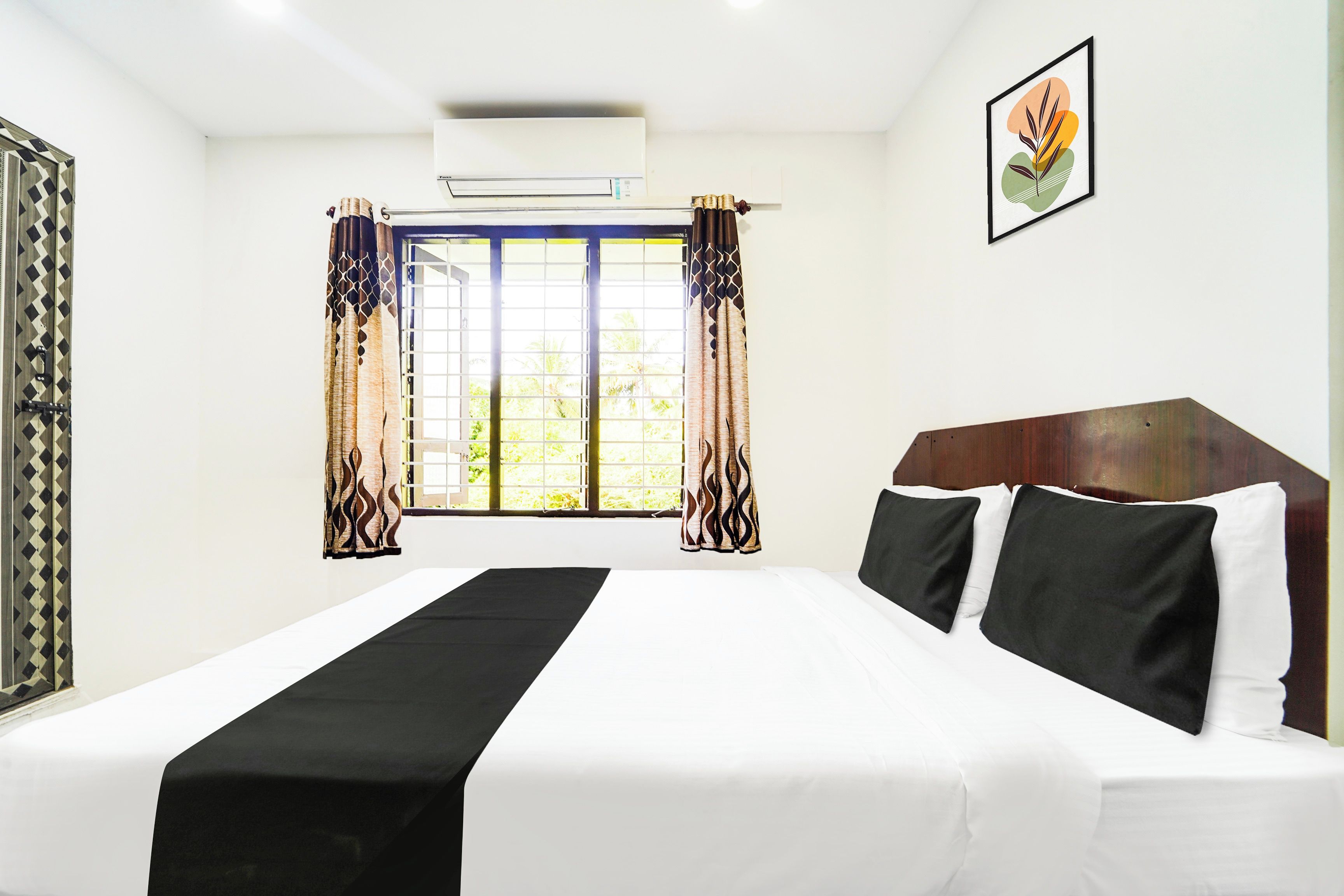 Quarto de hotel com cama, cortinas, janela e ar-condicionado fixado na parede.