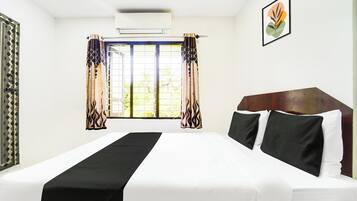 Quarto de hotel com cama, cortinas, janela e ar-condicionado fixado na parede.