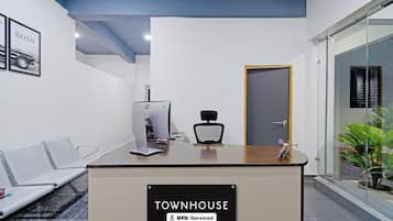 Uma mesa de recepção com a placa 'TOWNHOUSE' e um aviso indicando 'OYO-Serviced'.