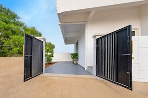 Uma entrada fechada por portão para um edifício, com uma galeria coberta que leva a uma porta.