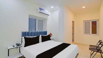 Quarto de hotel com cama, mesas de cabeceira, uma cadeira e ar condicionado.
