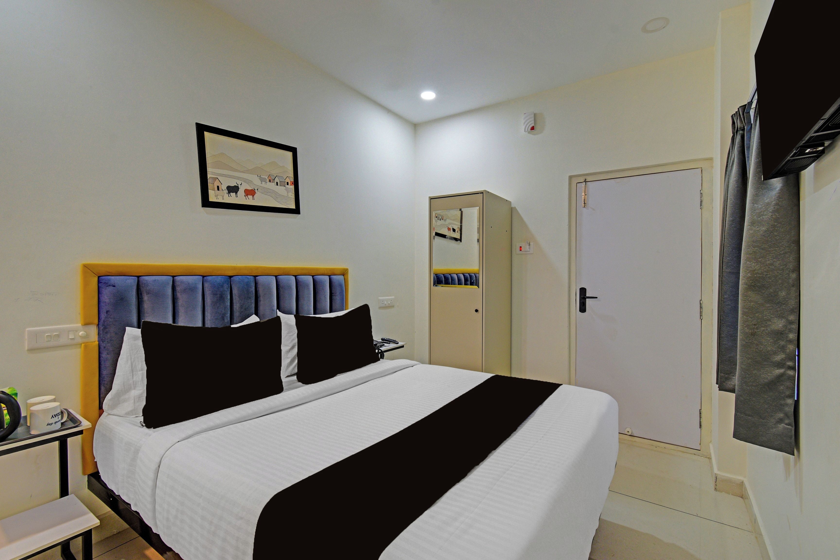 Quarto de hotel com cama, mesa de cabeceira, guarda-roupa e porta.