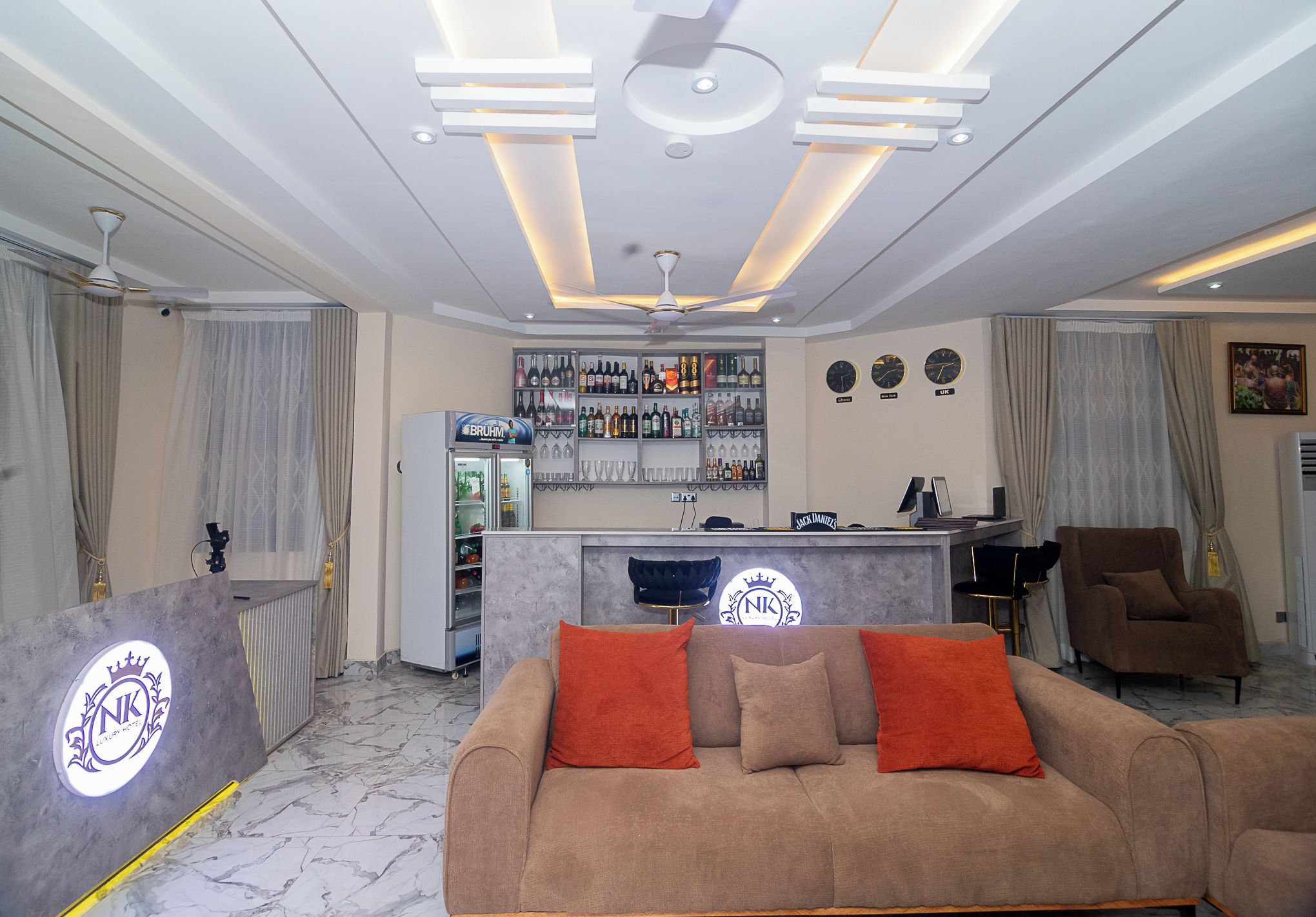 Uma sala de estar moderna com sofá, espaço de bar com garrafas de bebidas e geladeira.